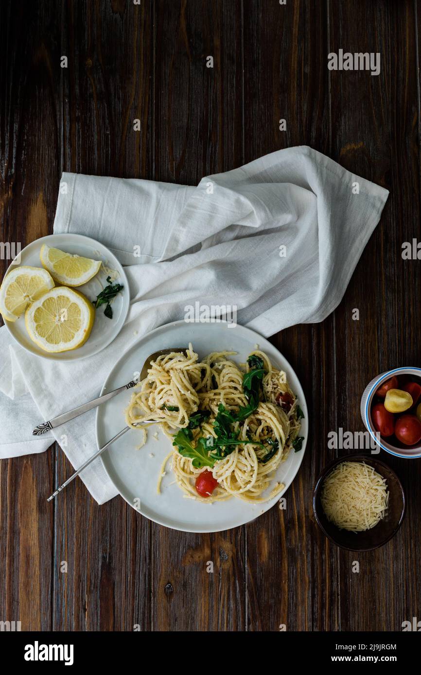 Spaghetti pasta on a wooden dinner table with white plates and napkins ...