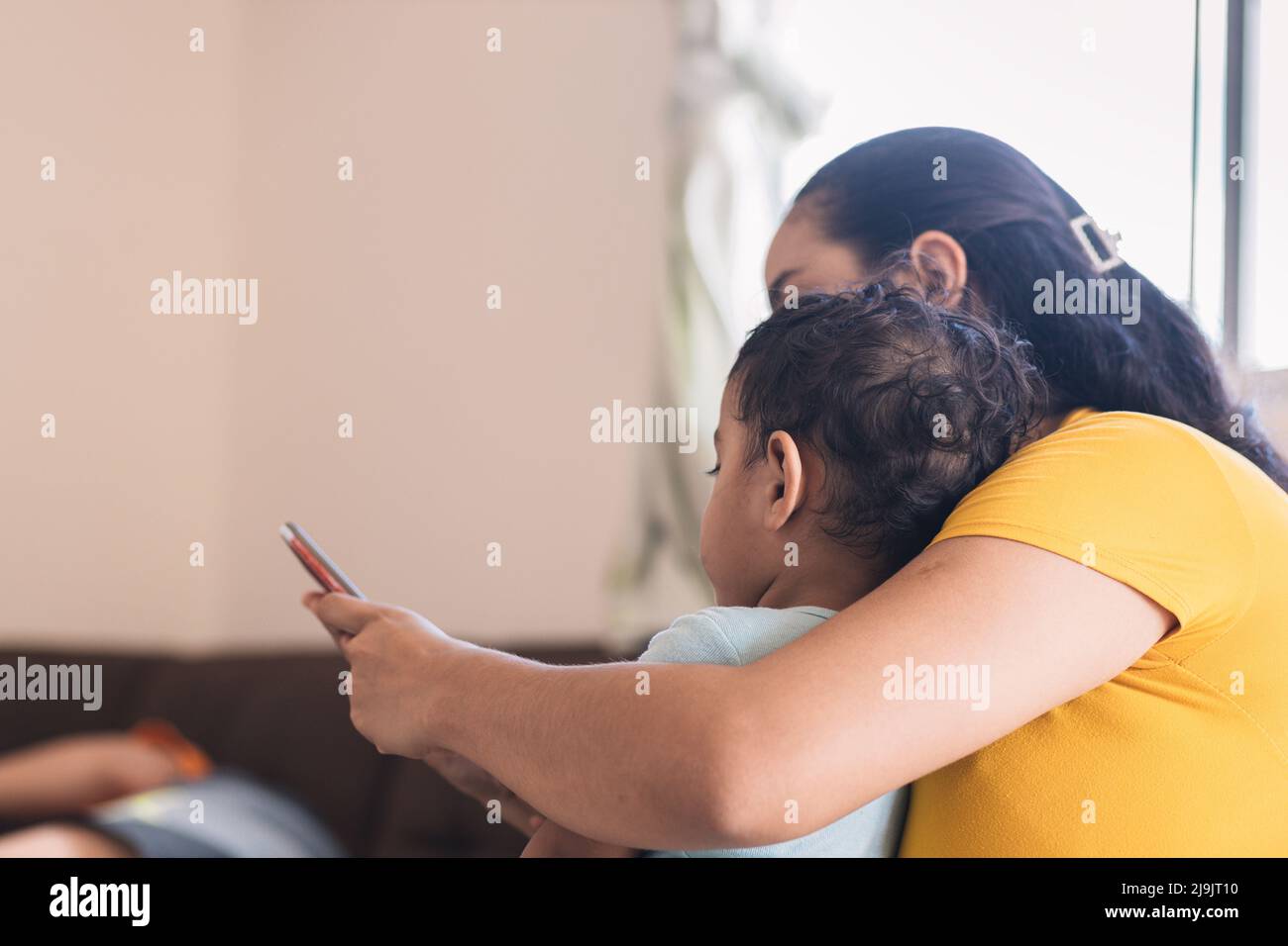 mom looking at the cell phone with her child Stock Photo - Alamy