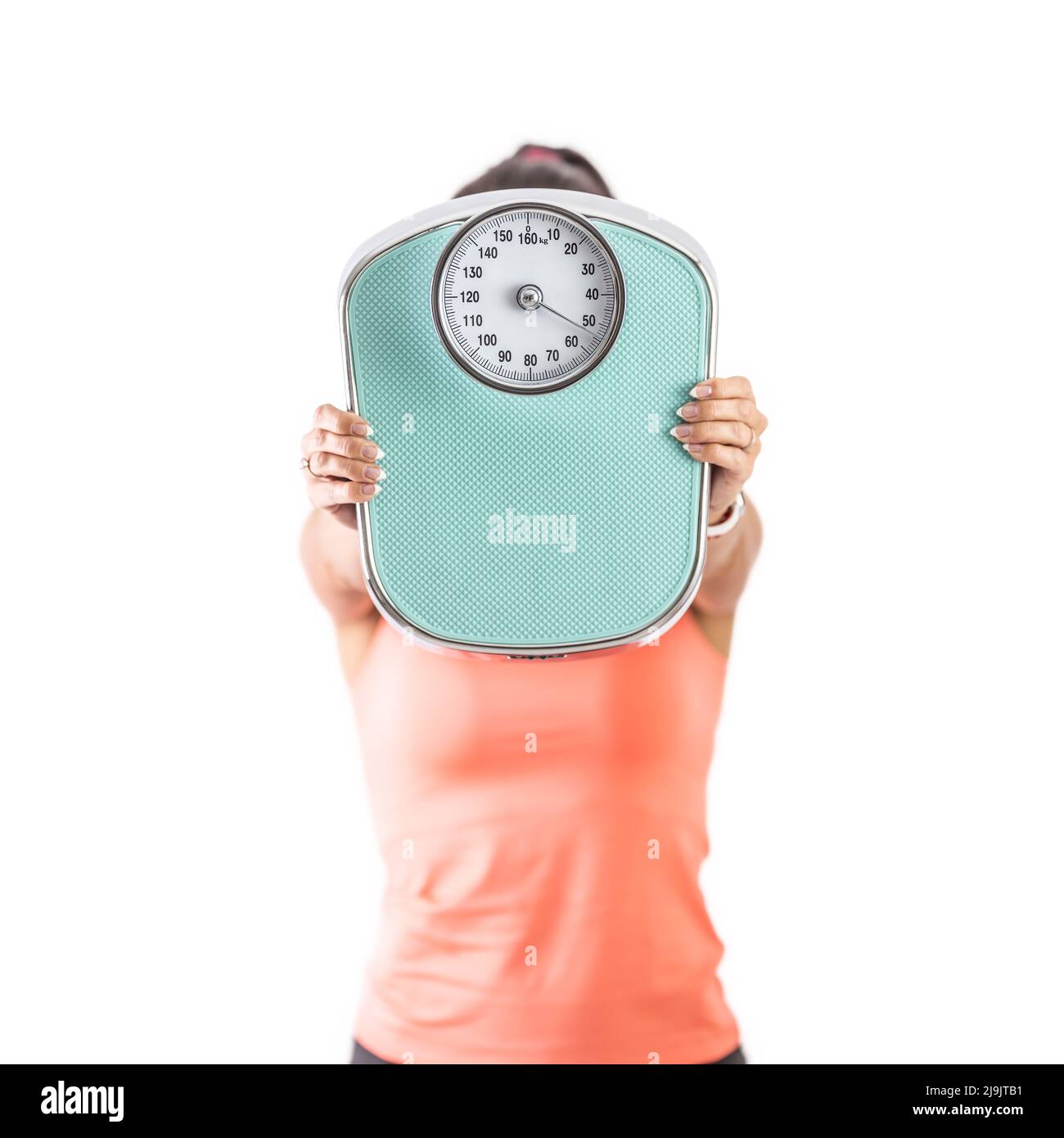 Woman holds a weighing scale against the camera covering her face with ...