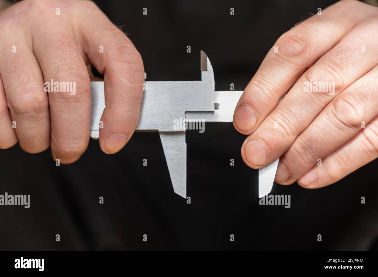 A man's hand holding a caliper. An adult man with a high-precision ...