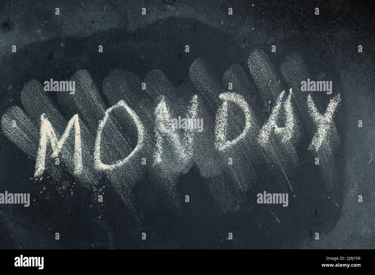 Semi-erased word MONDAY on black chalkboard. Handwritten word. Fuzzy ...