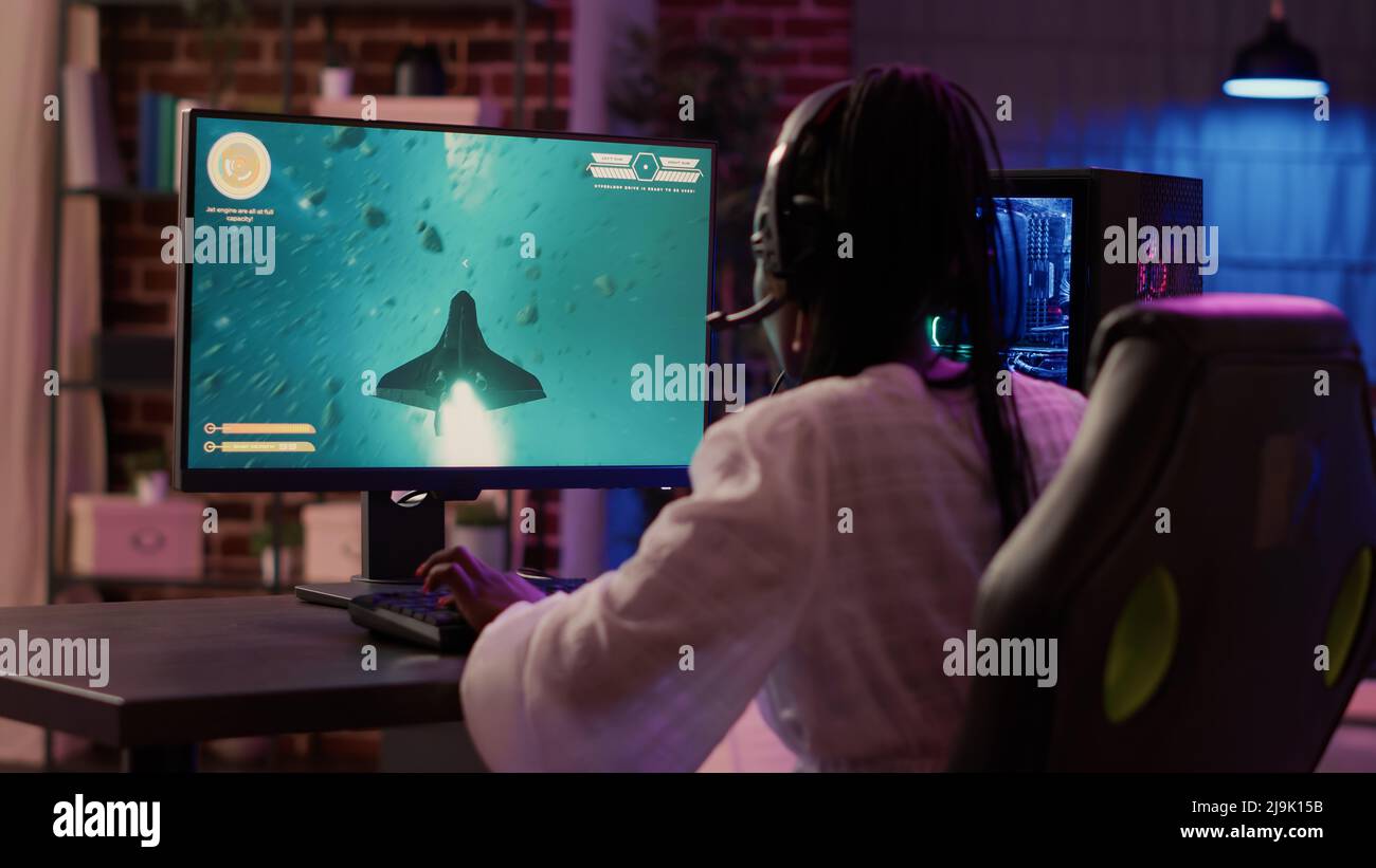 Over shoulder view of african american gamer girl playing space shooter ...