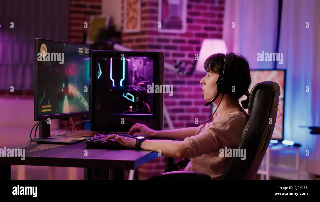 Caucasian gamer girl relaxing playing fast paced space shooter simulation on professional pc ...