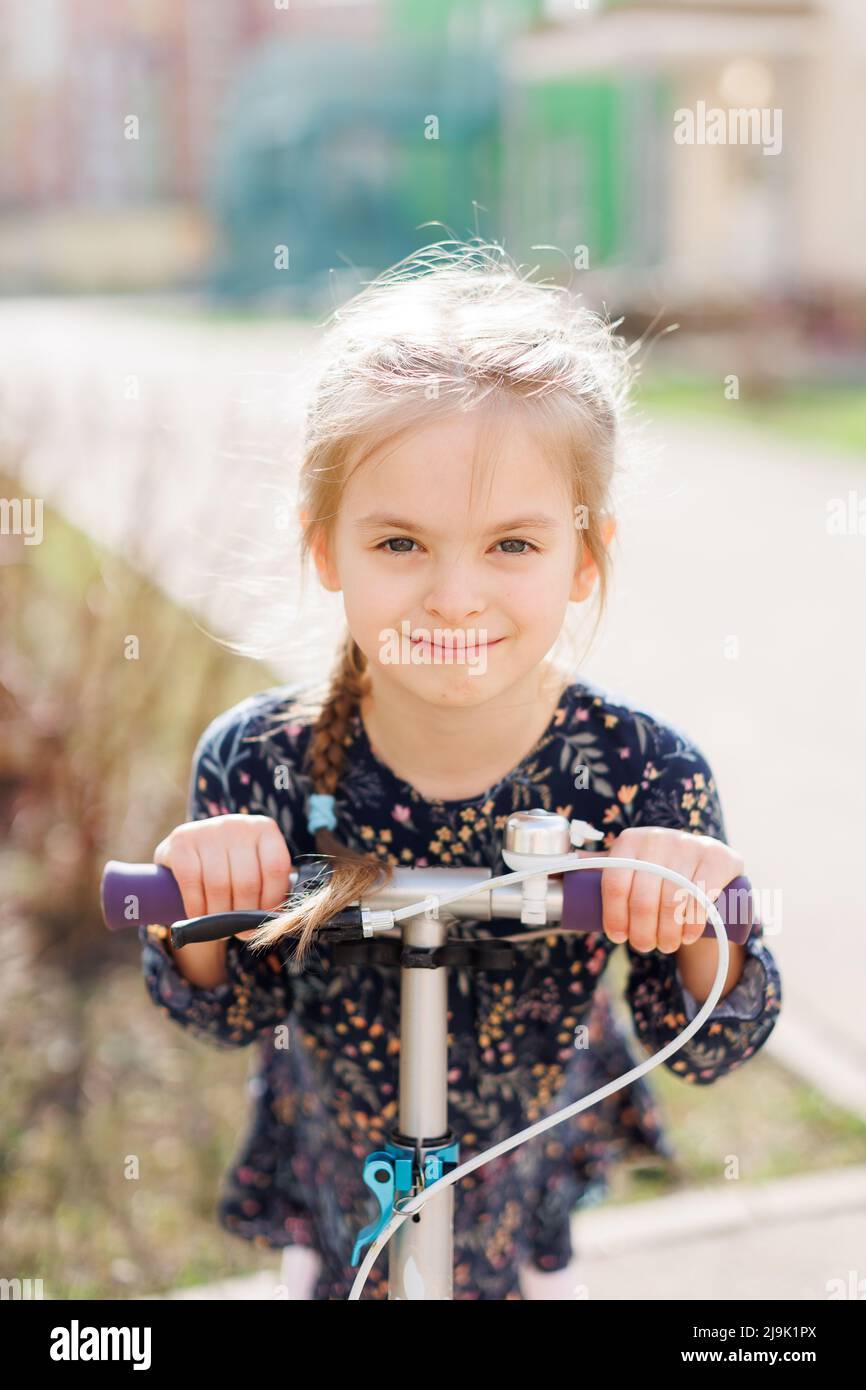 A cute blonde little girl is smiling at the camera. walking outside in ...