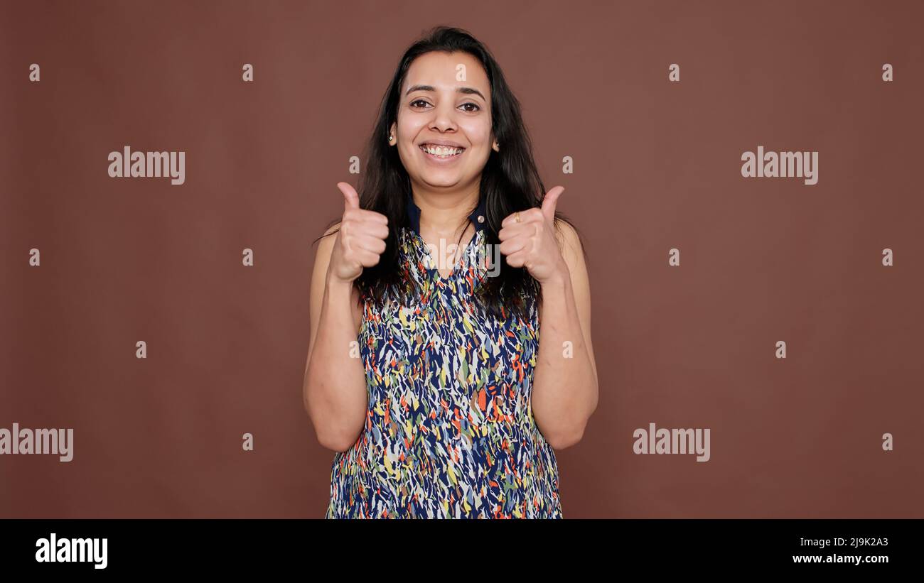 Indian model showing okay sign and thumbs up gesture in studio, giving ...