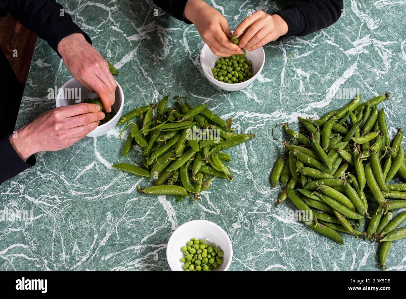 View from above mother and son shelling fresh organic green peas Stock ...