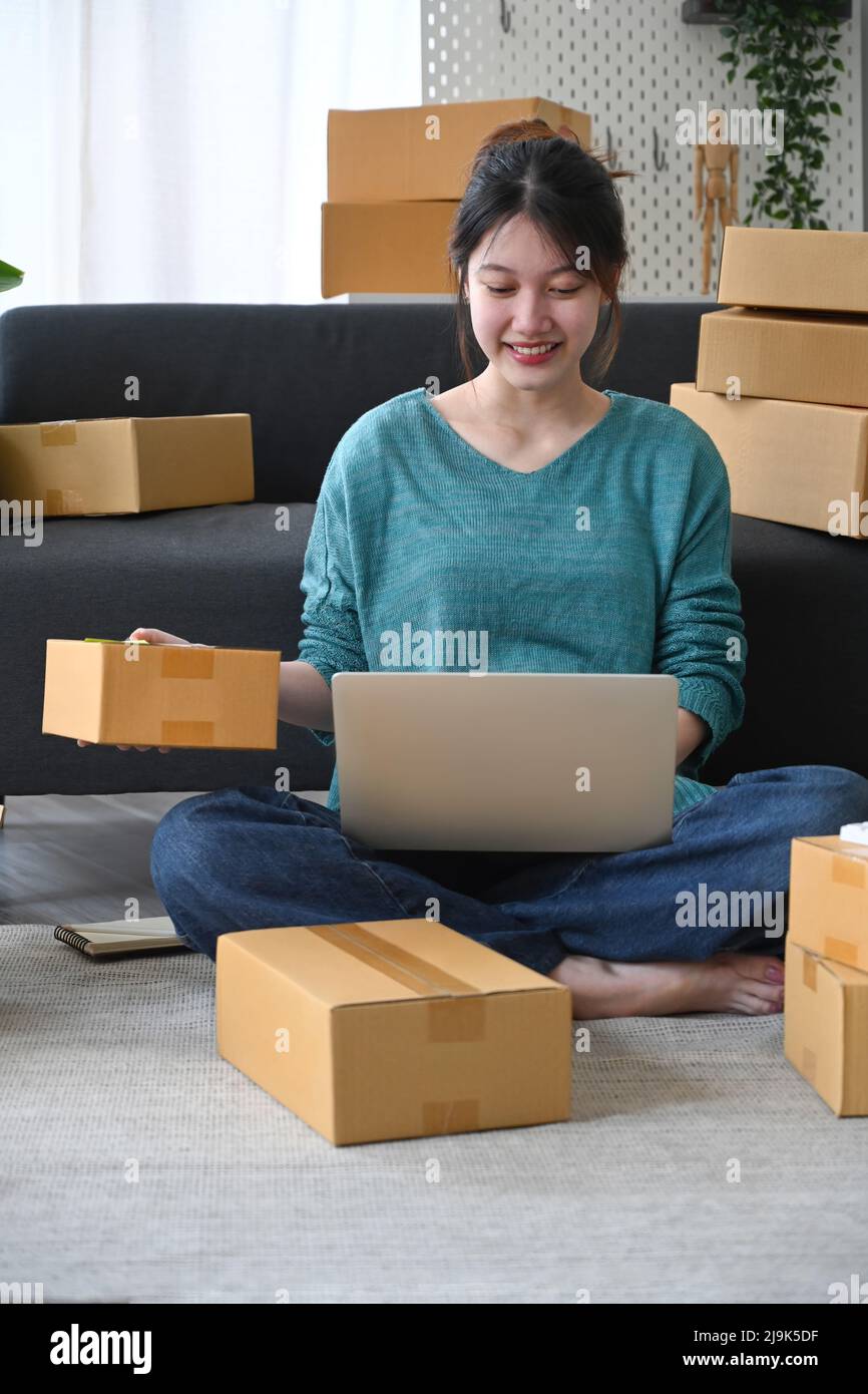 Smiling young man checking product purchase order on laptop computer ...