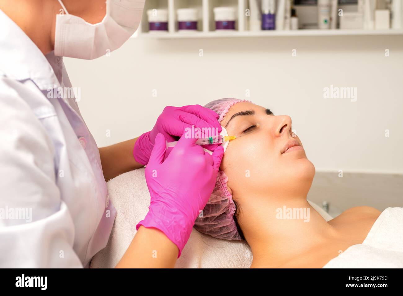 The young white woman is getting rejuvenating facial injections with ...