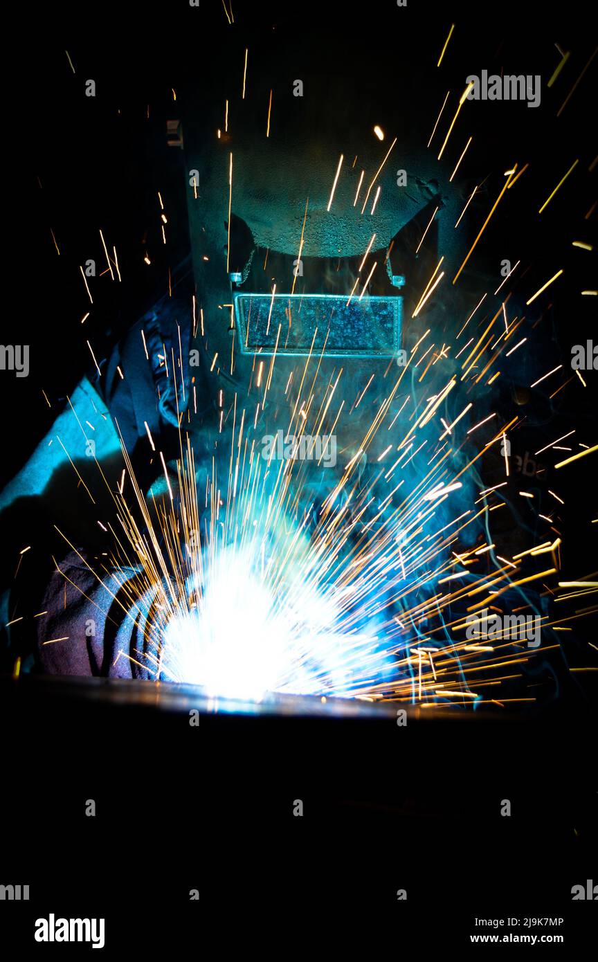 Welder uses torch to make sparks during manufacture of metal equipment, professional welding ...