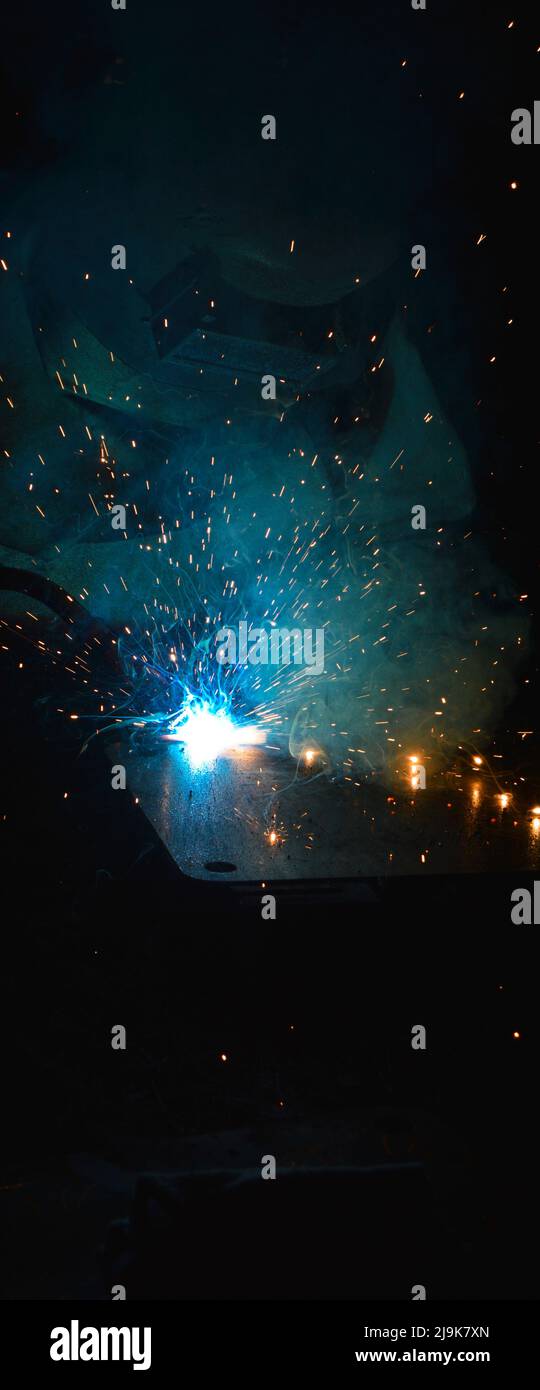 Welder uses torch to make sparks during manufacture of metal equipment ...
