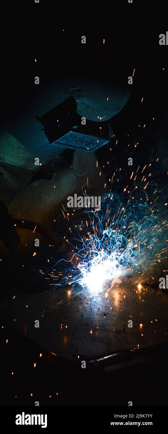 Welder uses torch to make sparks during manufacture of metal equipment ...