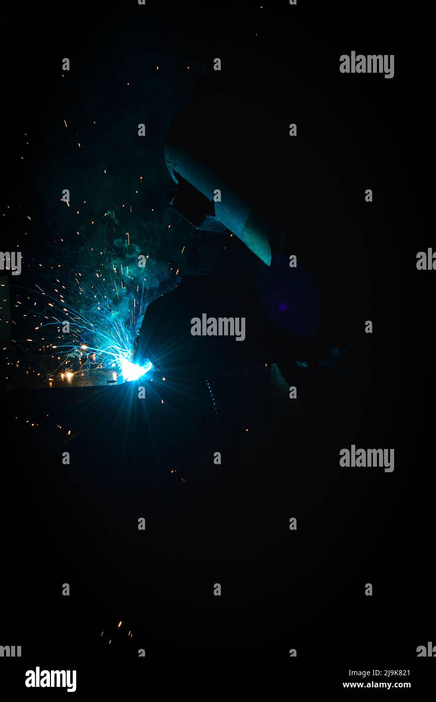Welder uses torch to make sparks during manufacture of metal equipment ...