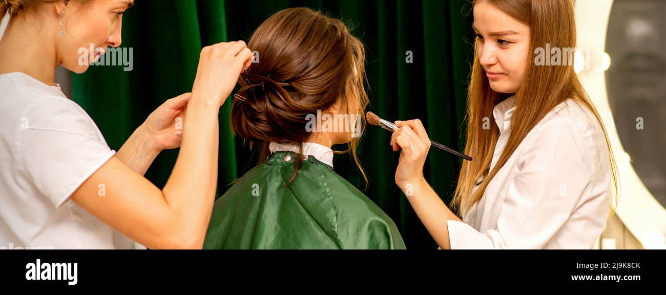 Makeup artist and hairdresser prepare the bride making hairstyle and ...