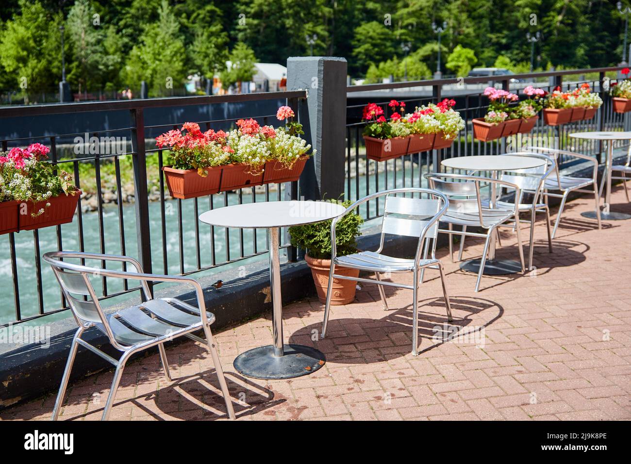 Summer cafe tables with flowers near the river Stock Photo - Alamy