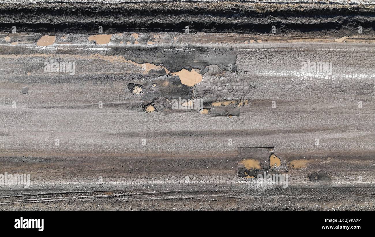 Broken old asphalt road outside the city. Pits and potholes. Aerial ...