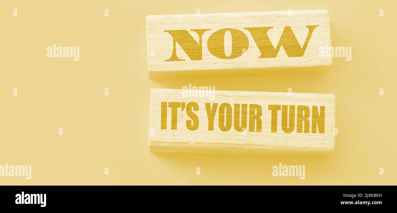Wooden blocks form the words Now it's your turn on yellow background ...