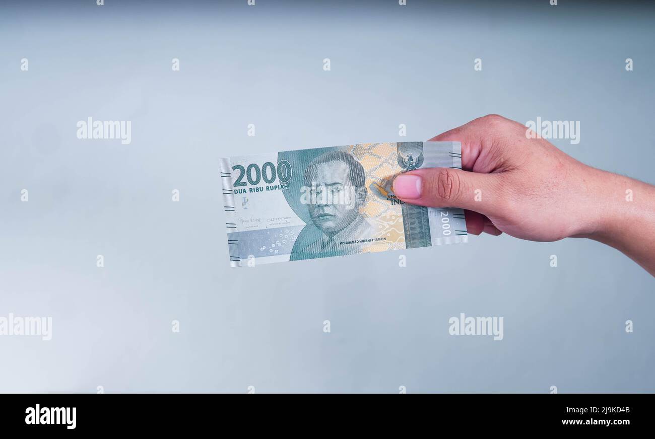 Hand holding indonesian rupiah banknote hi-res stock photography and ...