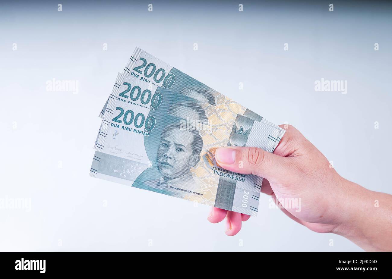 Hand holding indonesian rupiah banknote hi-res stock photography and ...