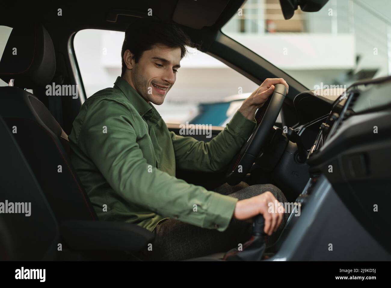 Happy young Caucasian man test driving new car before purchase at ...