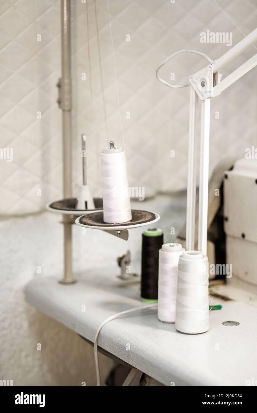 Reels with white threads for a sewing machine on a stand in atelier ...