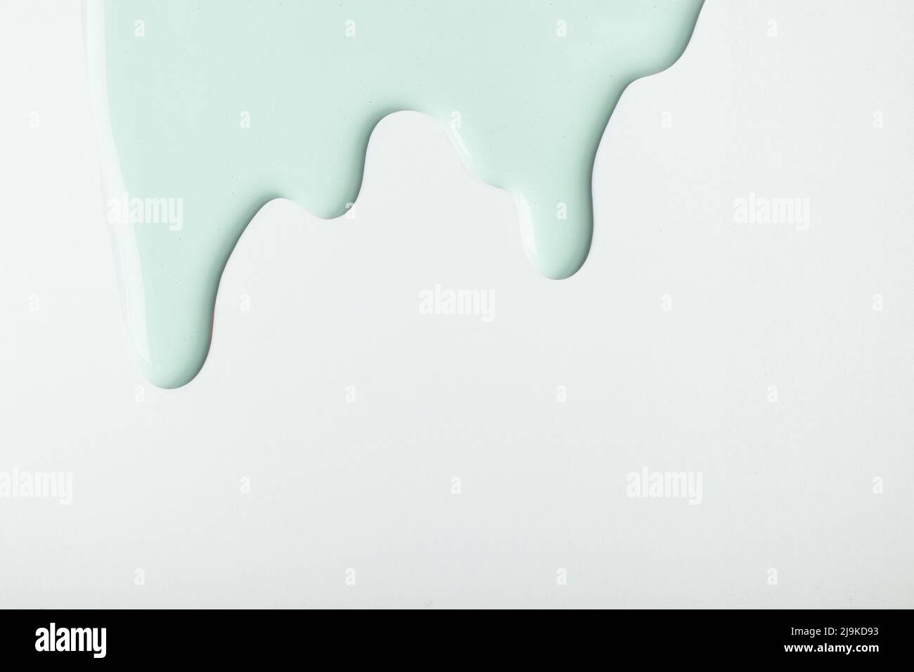 Light cyan liquid drops of paint color flow down on isolated white ...