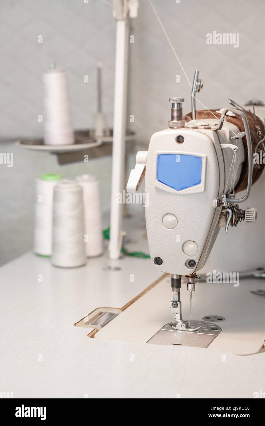 Sewing machine close-up on the background of coils with white threads ...