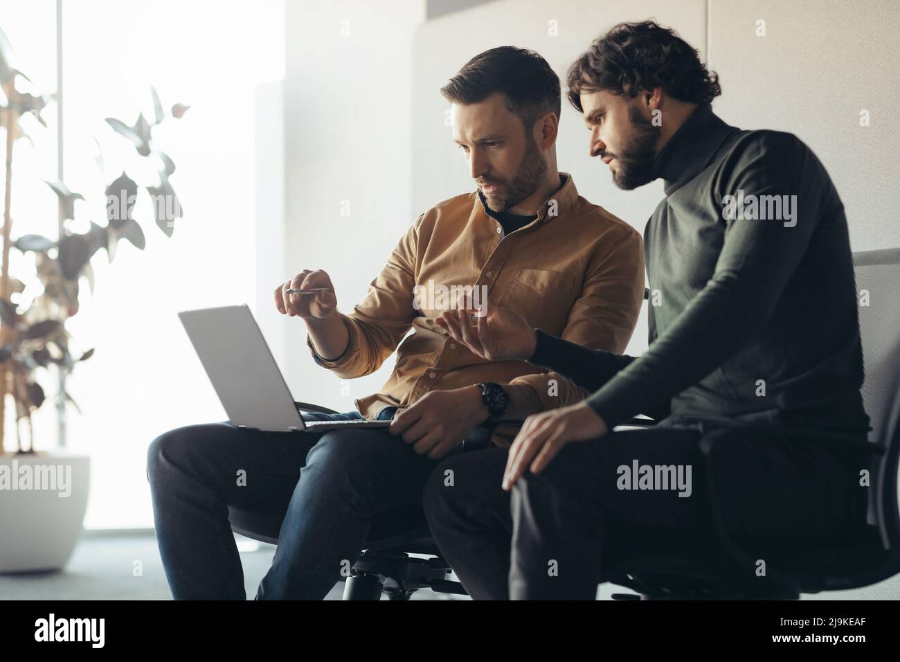 Focused company employees looking at laptop screen, working on business ...