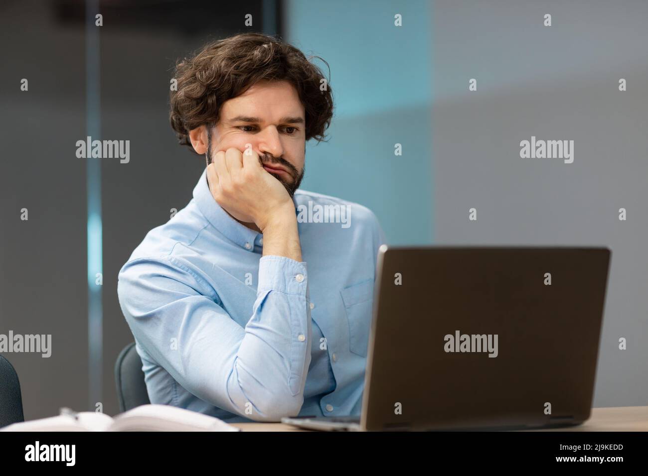Bired business man leaning head on hand using pc Stock Photo - Alamy