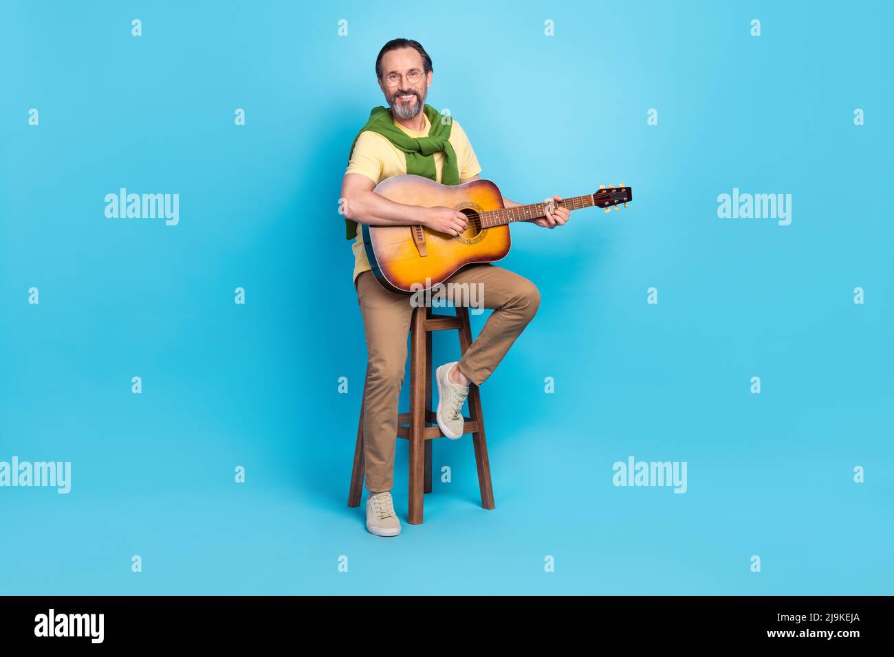 Full size photo of cheerful musician sitting chair playing singing ...