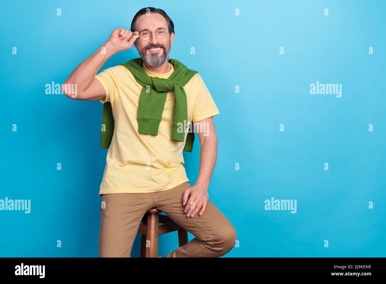 Portrait of satisfied glad person sit chair hand touch eyeglasses ...