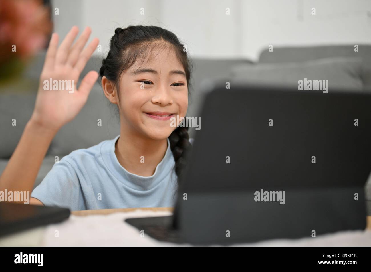 Happy Asian young little girl saying hi greeting her friends and ...