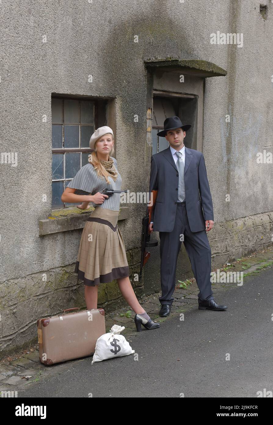 A young couple get dressed up in 1930 style clothing. They each carry a ...
