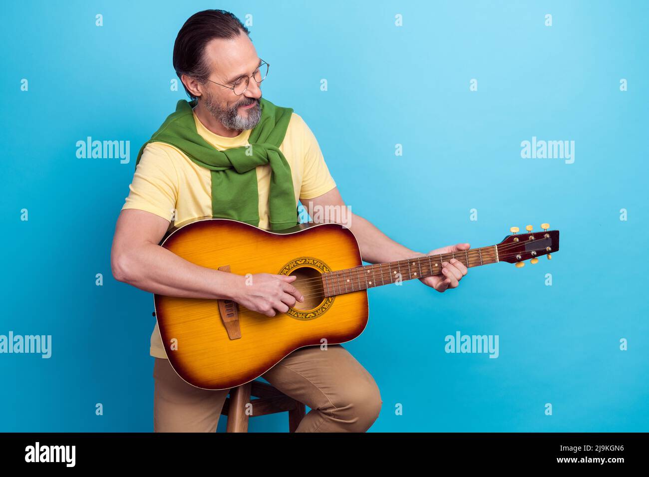 Portrait of positive man sitting chair playing acoustic guitar sing ...