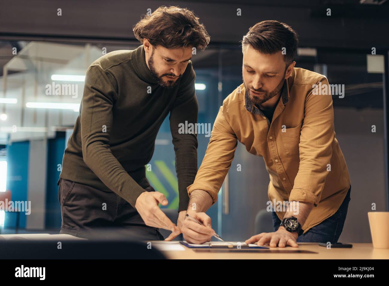 Male colleagues working on business project together as team, noting ...