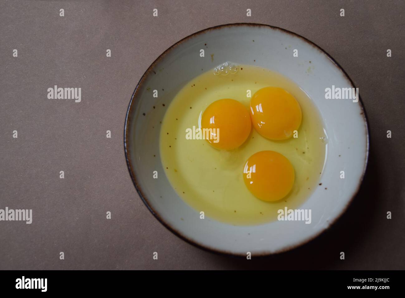 bowl with three raw eggs Stock Photo - Alamy
