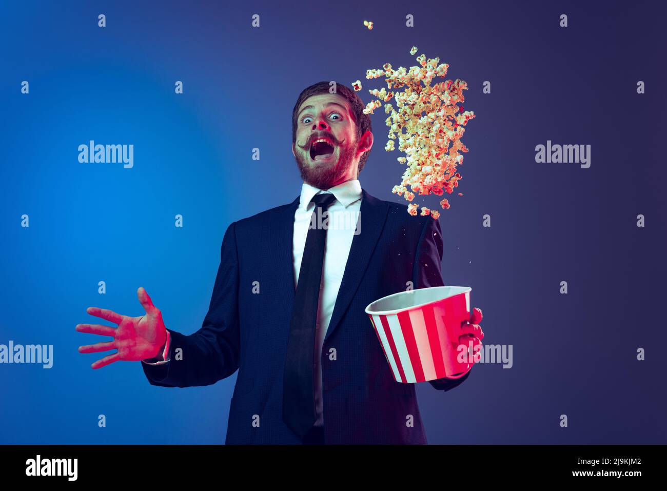 Young scared man in business suit eating popcorn and watching movie ...
