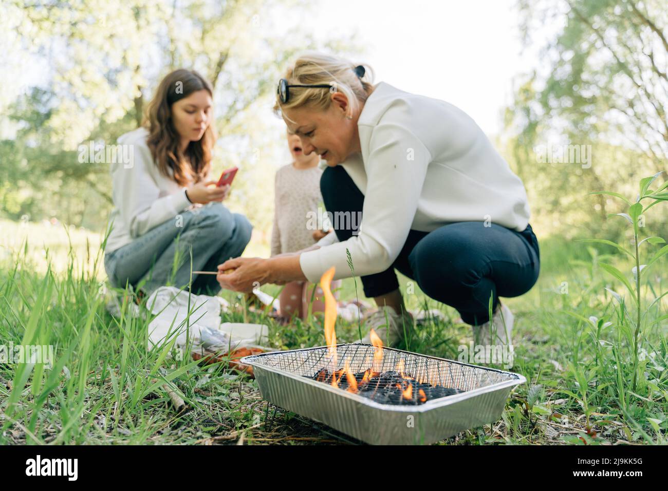 Family with small child, teen and grandmother doing bbq on the nature ...
