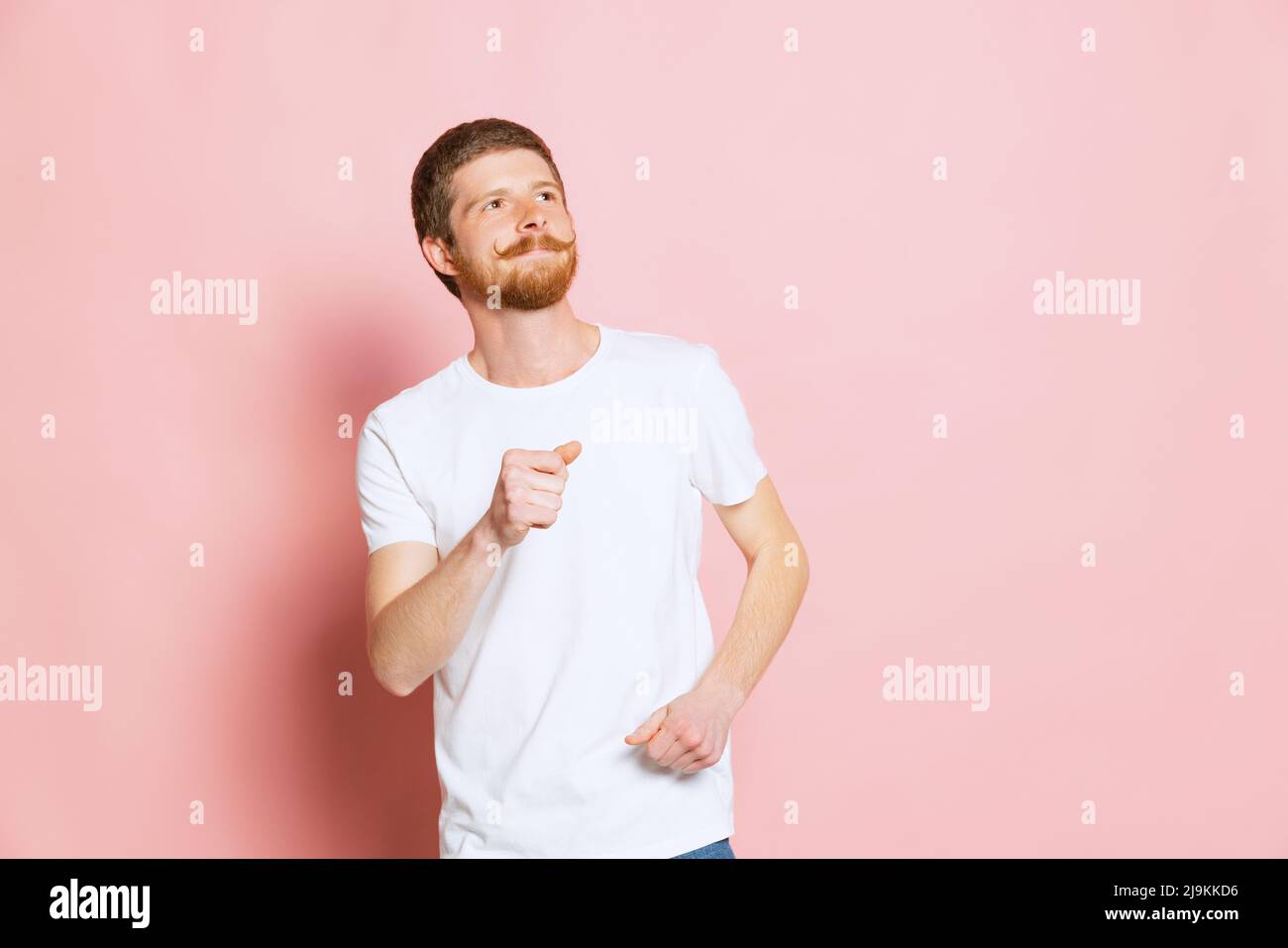 Portrait of young happy red-headed man in white t-shirt posing isolated ...