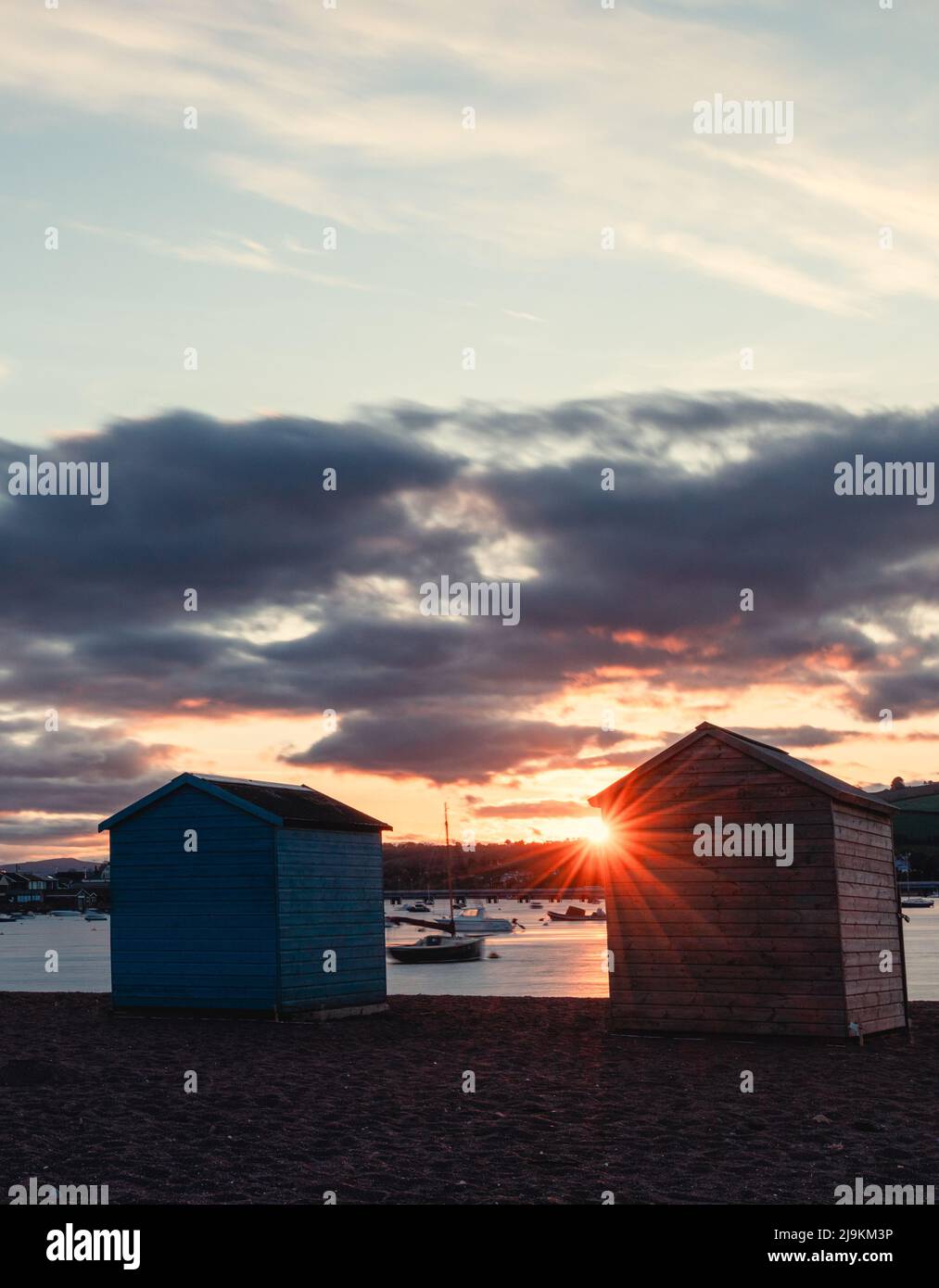 Beach huts at sunset on Teignmouth's 'back beach' with the seafront of ...
