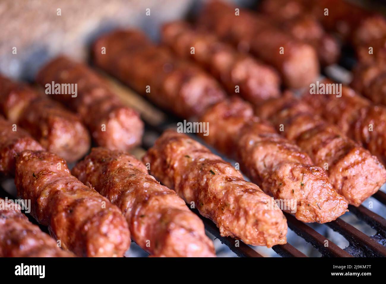 Preparing meat rolls called mici or mititei on barbecue. close up of ...