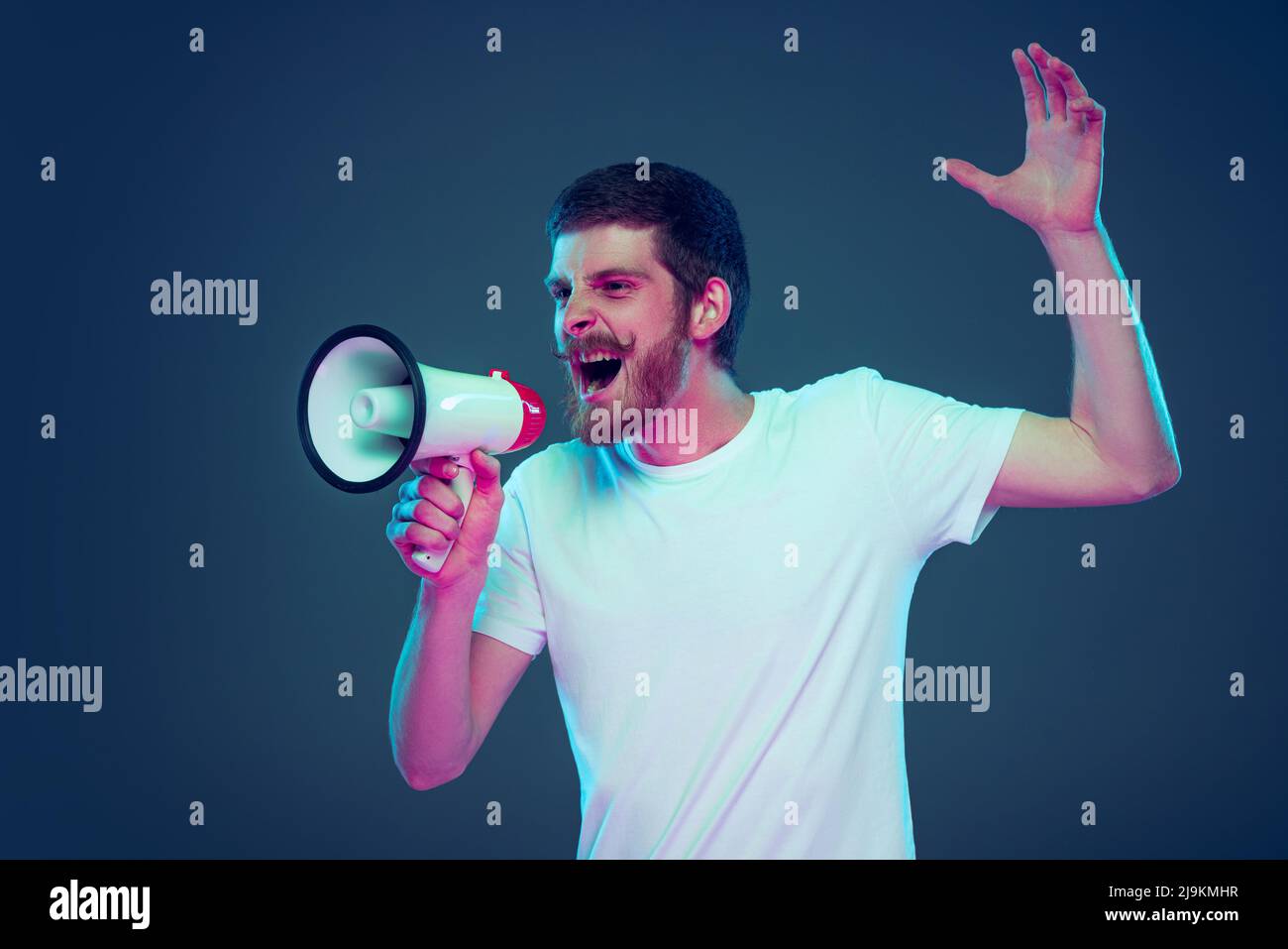 Guy shouting at megaphone. Handsome caucasian man's portrait isolated ...