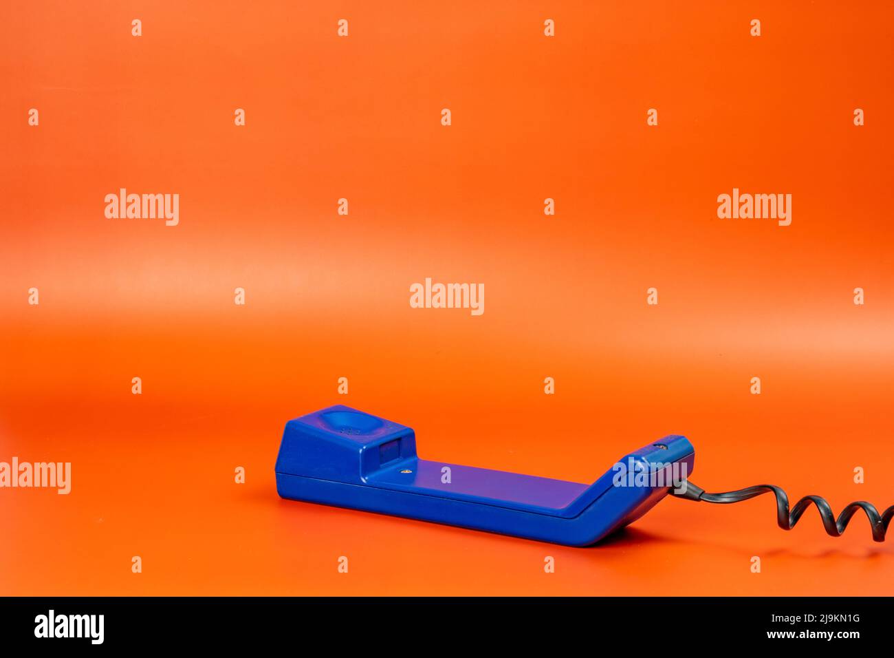 Antique blue corded telephone on an orange background Stock Photo - Alamy