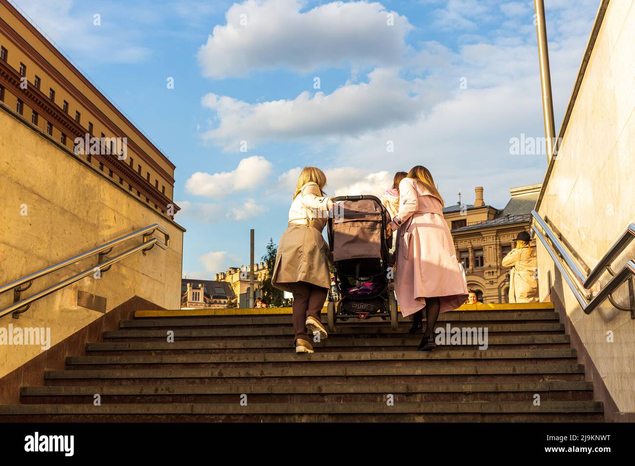 Moscow, Russia - 22 May 2022, Two girls lift a stroller up the steps ...