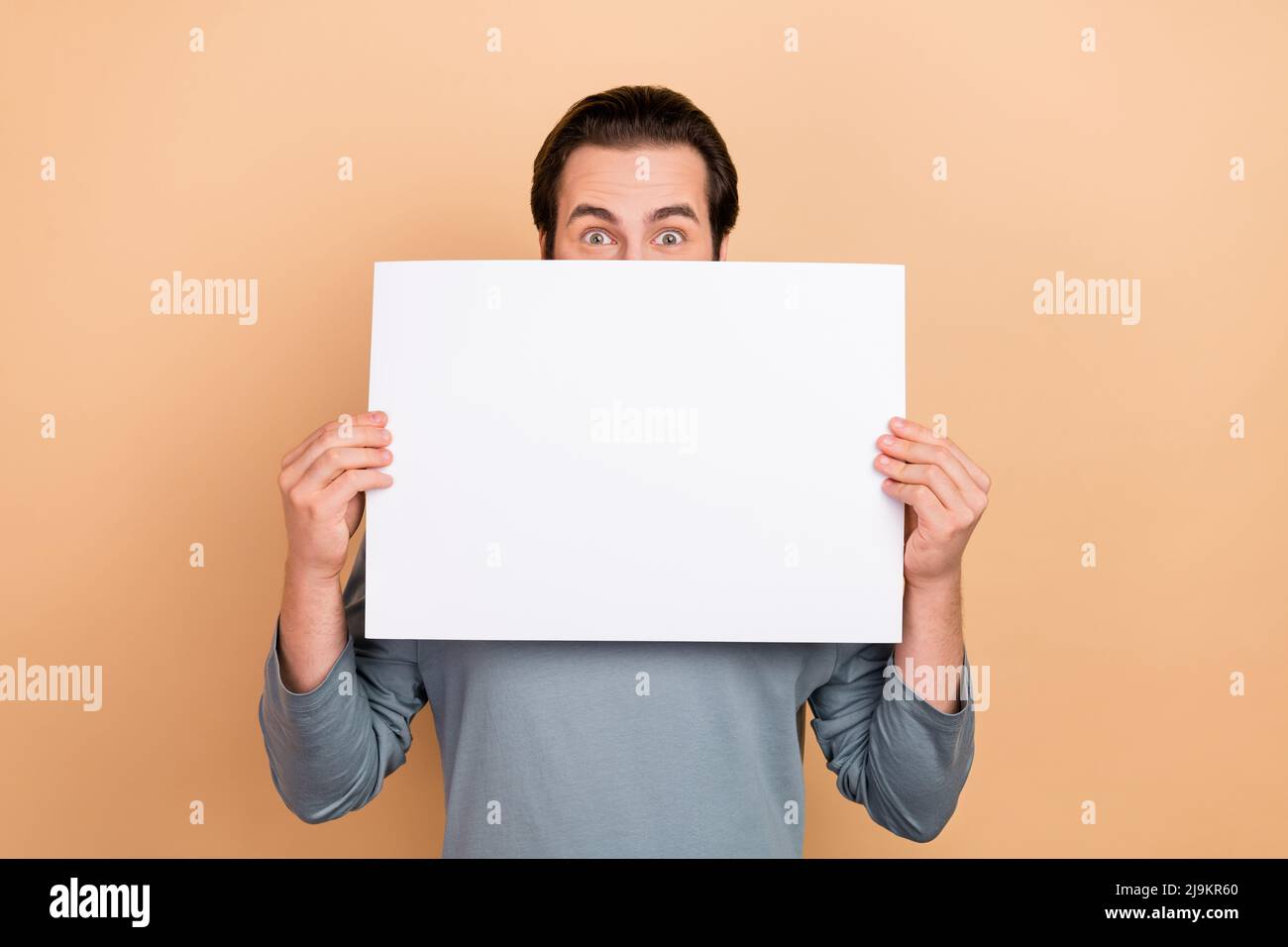 Photo of young guy cover half face white paper banner ads promotion ...