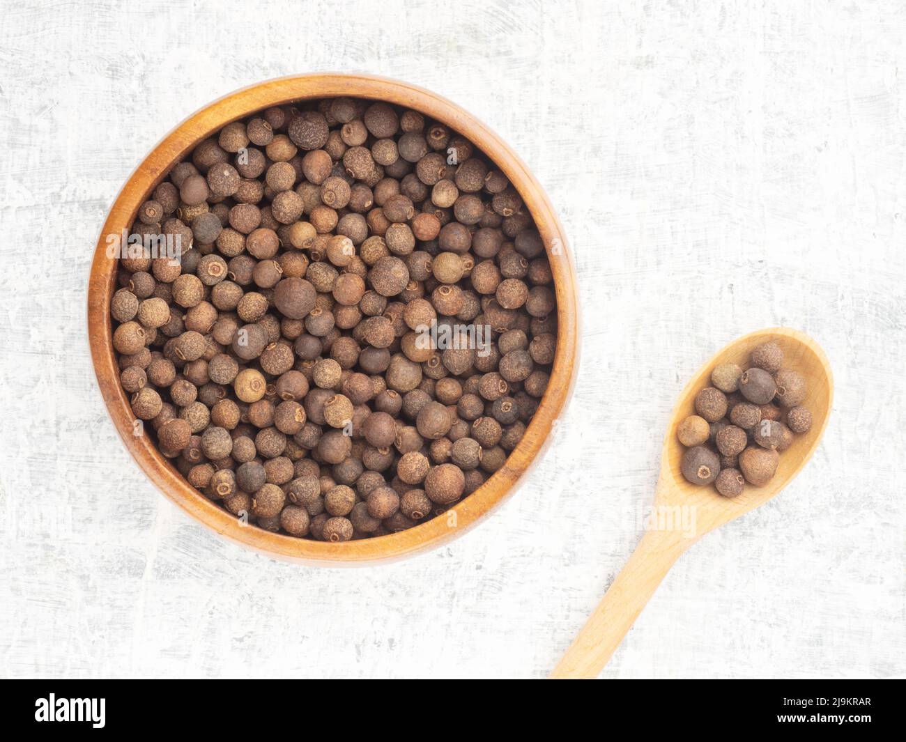 Spice Allspice (Jamaica pepper, Pimento) in wooden bowl, spoon on white ...