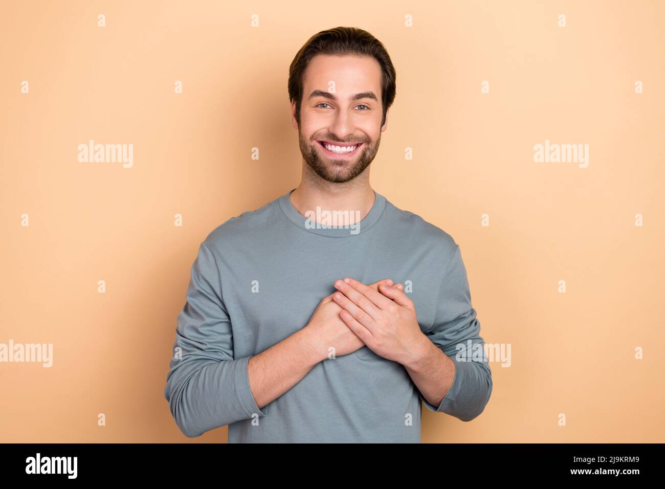 Photo of young cheerful man arms on chest pray hope appreciate thankful ...