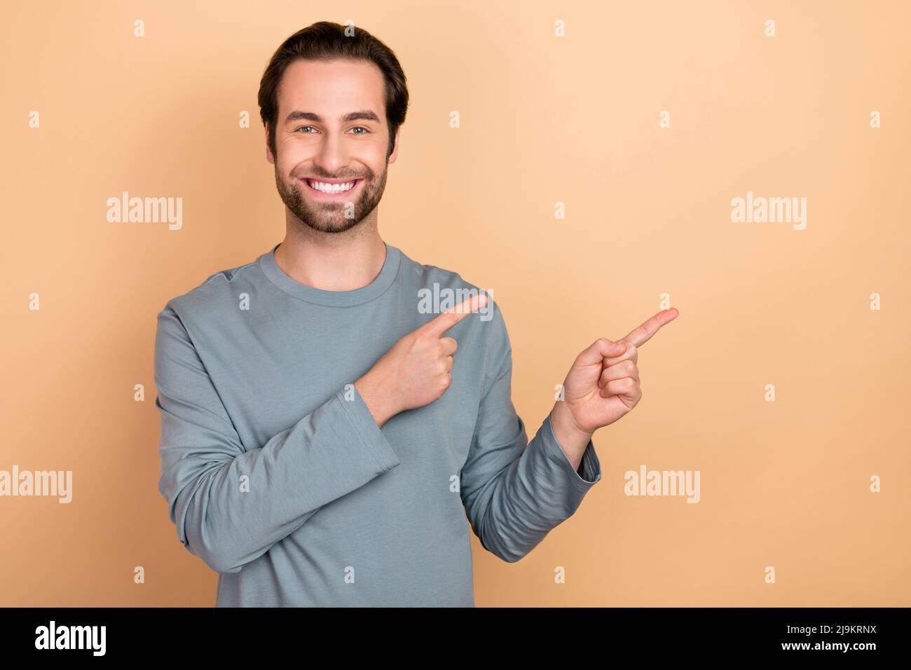Photo of young cheerful man indicate fingers empty space banner direct ...