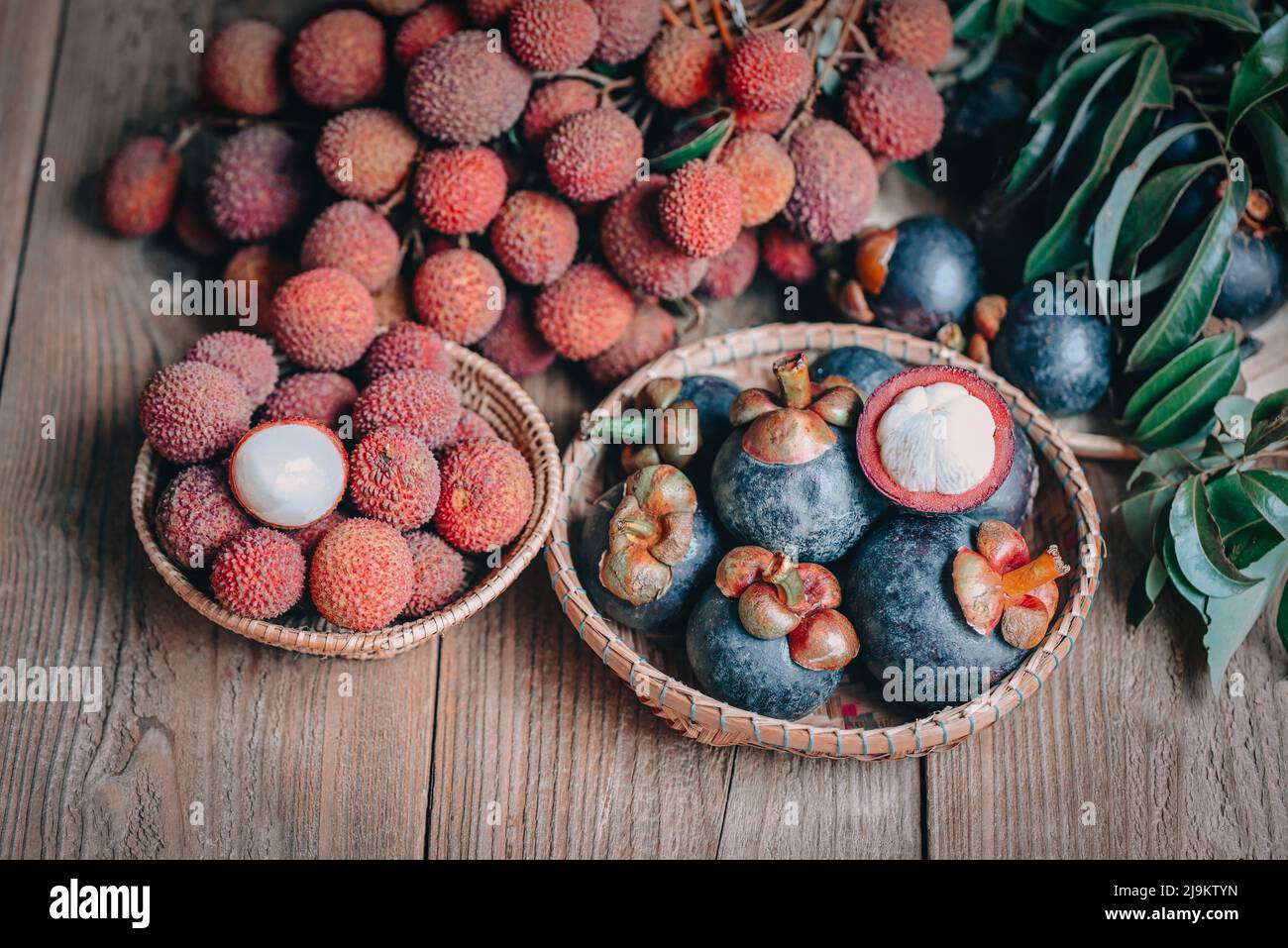 Lychee fruit and mangosteen on basket with green leaf and wooden ...