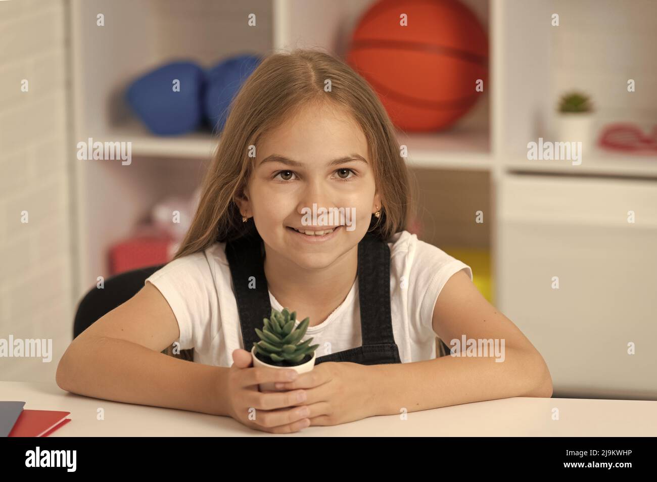 happy child holding plant in pot at school classroom on lesson ...