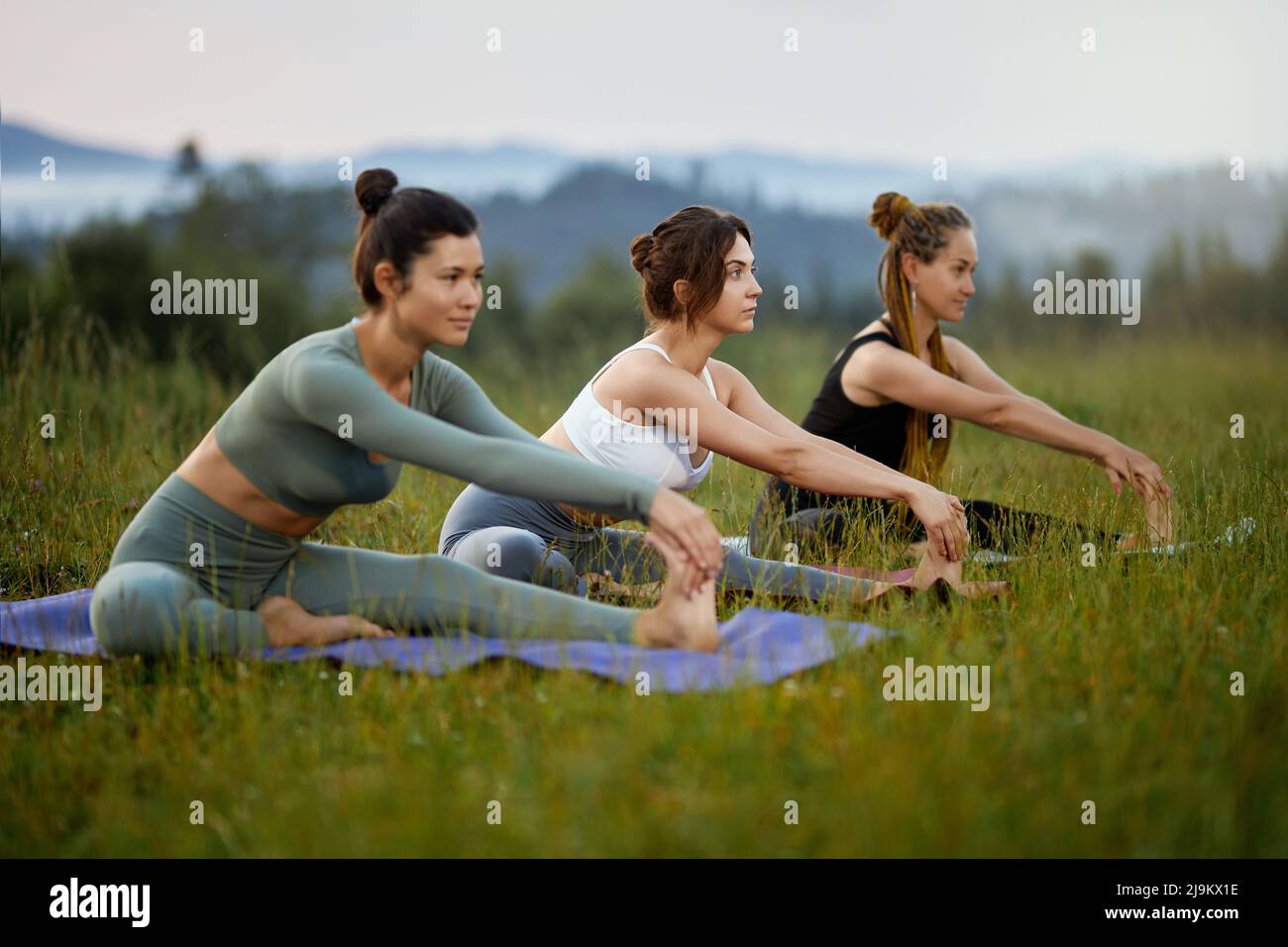 Side view of sporty females bending leg at knee stretching back and leg ...